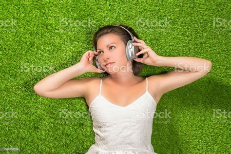 흰색 드레스와 헤드폰을 입은 아름다운 젊은 여성이 잔디 위에 누워 음악을 듣습니다 여름 컨셉 위에서 보기 건강한 생활방식에 대한