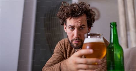 퇴근 후 소파에 앉아 차가운 맥주를 마시는 우울한 남자 잔을 들고 있는 손 혼자 집에 술을 마시는 남자 알코올 중독 알코올 중독 및 사람 개념 사진