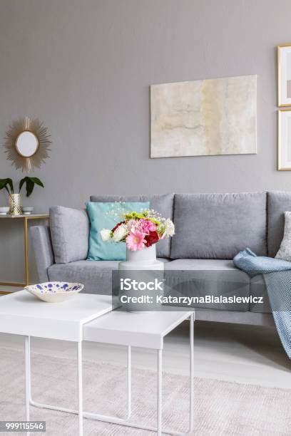금속 테이블 회색 소파에 블루 베개와 밝은 거실 인테리어에 흰색 꽃병 서에서 꽃의 꽃다발 실제 사진 소파에 대한 스톡 사진 및