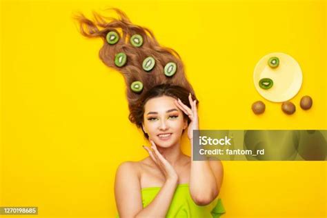 긴 머리 사람 및 음식에 키위 과일 조각과 색깔의 배경에 누워 아름다운 소녀의 패션 초상화 젊은 평화로운 여자는 아름다움과 몸을 돌봅니다 가리기에 대한 스톡 사진 및 기타