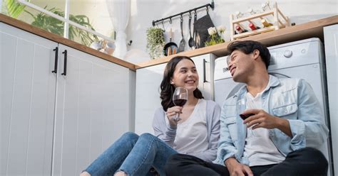 아시아의 젊은 신혼 부부는 집에서 부엌에서 함께 시간을 보낸다 매력적인 낭만적 인 남자와 여자는 가족 관계 생활과 새 집으로 이사하는 것을 축하하기 위해 와인을 마신다