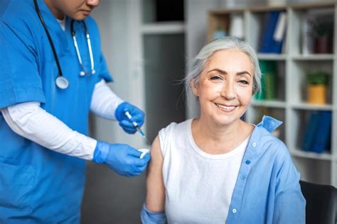 Premium Photo Millennial Man Doctor Make Injection To Smiling Elderly