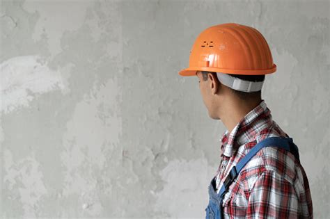 벽을 바라 보는 회색 배경 위에 머물고있는 복사 공간을 가진 자신감있는 잘 생긴 남성 건설 노동자 18 19세에 대한 스톡 사진 및 기타 이미지 Istock