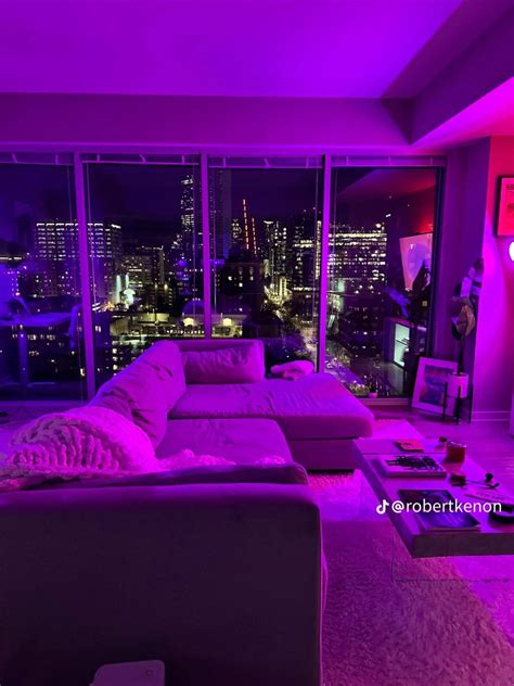 A Living Room With Purple Lighting And Large Windows Overlooking The