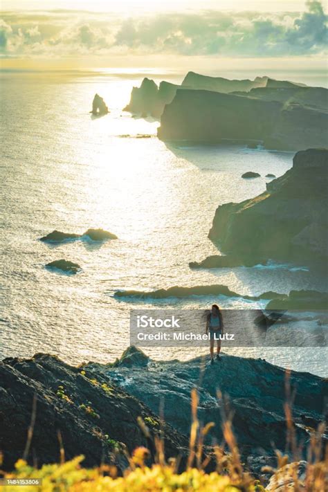 배낭 여행자는 바다 경치 위의 가파른 절벽과 일출에 마데이라 해안의 험준한 산기슭을 따라 하이킹을 즐깁니다 Ponta Do