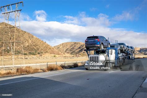 분할된 고속도로 도로에서 달리는 모듈식 세미 트레일러에서 크로스오버 자동차를 운반하는 강력한 클래식 대형 장비 자동차 운반기 세미 트럭 0명에 대한 스톡 사진 및 기타
