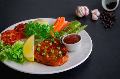 흰색 접시에 바베 큐 돼지고기 스테이크 바베 큐 소스와 야채와 함께 제공 됩니다 점심이 나 저녁 식사 화강암 테이블에는 돼지고기 스테이크 매 시 감자와 야채와 함께 촉 촉