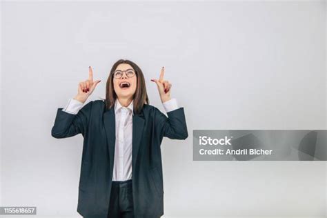 검은 양복을 입고 서서 미소를 지으며 위를 올려다 보며 텍스트 나 제품의 카피 스페이스에서 손가락을 가리키고있는 예쁜 젊은 사업가 가리키기에 대한 스톡 사진 및 기타 이미지