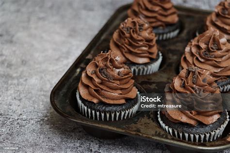 수제 초콜릿 컵케이크가 들어있는 머핀 케이크 주석의 이미지 초콜릿 버터 아이싱 파이프 소용돌이 초콜릿 조각 회색 배경 높은 전망 전경에 초점 복사 공간 컵케이크에 대한 스톡
