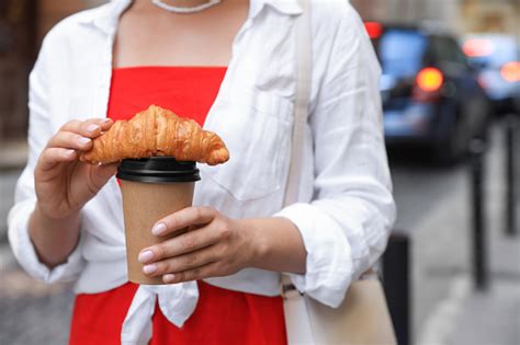 도시 거리에서 맛있는 크루아상과 커피 한 잔을 들고 있는 여자 크루아상에 대한 스톡 사진 및 기타 이미지 크루아상 먹기 거리 Istock