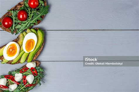 신선한 아보카도 채소와 Arugula와 삶은 달걀을 곁들인 모 짜 렐 라 치즈와 튀긴 토스트 회색 나무 배경에 복사 공간 평 신도를 위한 장소가 있는 샌드위치의 다양 한 0