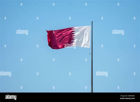 Qatar National Flag Waving Against A Clear Blue Sky The Maroon And White Flag Of Qatar Is