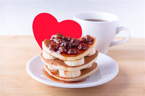 흰색 접시에 베리 잼과 바나나를 곁들인 홈메이드 하트 모양의 팬케이크 포크 커피와 하트가 있는 머그컵 개념에 대한 스톡 사진 및