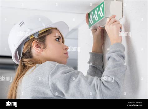 Woman Fixing Exit Sign To Wall Stock Photo Alamy