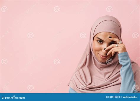A Positive Muslim Woman In Pink Hijab Covering Her Face And Looking At