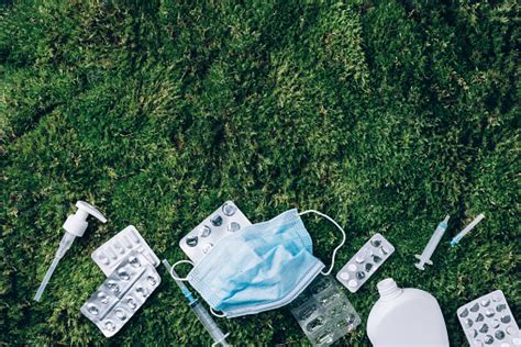 일회용 의료 용 얼굴 마스크 라텍스 의료 장갑 약물 커버 녹색 잔디 배경에 주사기 사용 맨 위 보기입니다 공간을 복사합니다