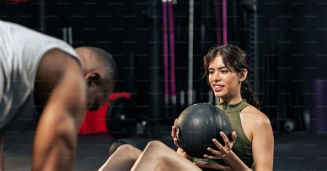 라틴계 젊은 아름다운 스포츠 여자는 트레이너의 도움으로 운동 매력적인 아프리카 계 미국인 트레이너 남성 코칭 여성은 볼 장비를 사용하여 근육을 유지하고 경기장에서 신체를