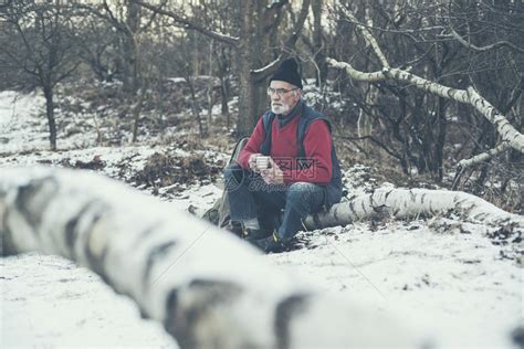 孤独的老人坐在雪地里倒下的树干上高清图片下载 正版图片503585532 摄图网