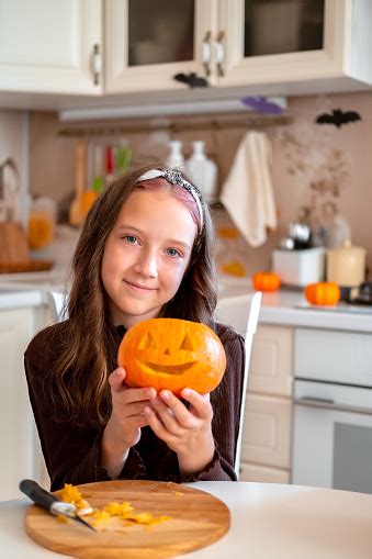 집에서 밝은 흰색 부엌에서 호박에 유령 같은 얼굴을 조각하는 칼을 들고있는 귀여운 10 세 소녀 할로윈 준비 아이에 대한 스톡 사진 및 기타 이미지 Istock