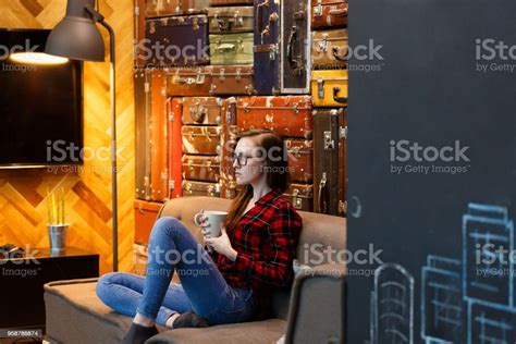 아름 다운 젊은 여성 캐주얼 의류와 안경 음료 커피 현대적인 인테리어의 배경에서 소파에 앉아 벽의 오래 된 가방 노트북에 대한 스톡 사진 및 기타 이미지 Istock