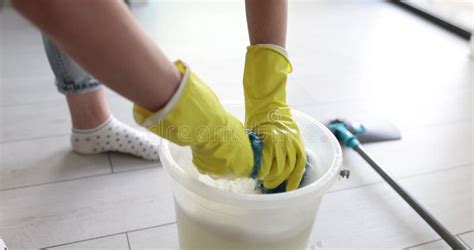 Housewife In Rubber Gloves Squeezes Rag With Mop Over Bucket In Room