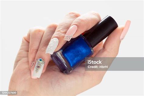 매니큐어 아트 매니큐어 현대 스타일 산호 흰색 매니큐어 파란 병을 들고 있는 미용손 세련 된 파스텔 컬러 핑크 화이트 손톱 고립 된 흰색 배경입니다 클래식 웨딩 신부 손톱