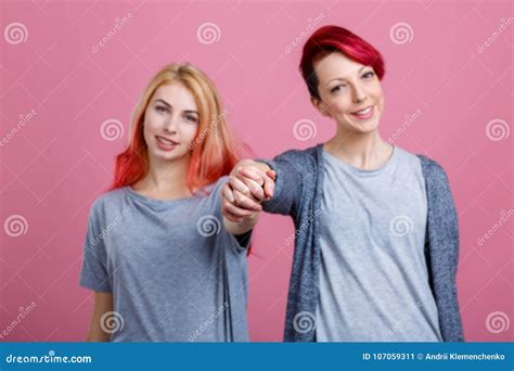 Tenendosi Per Mano Di Due Ragazze Lesbiche Su Un Fondo Rosa Immagine