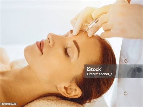 햇볕이 잘 드는 의료 센터에서 눈을 감고 미용 주사를받는 아름다운 여성 미용사 의사 손 과 미용 절차 에 여성 얼굴 와 주사기 건강관리와 의술에 대한 스톡 사진 및 기타