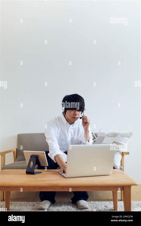 Man Operating Computer And Tablet With Intercom In Living Room Stock