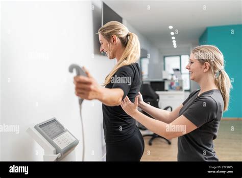 Trainer Assisting A Client On A Body Composition Medical Scale For A Inbody Test In A Gym Both