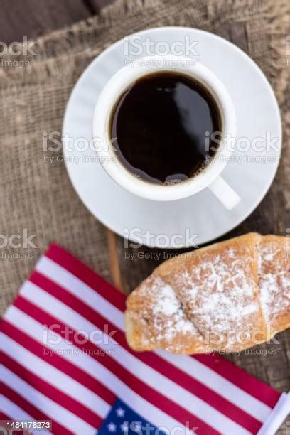 커피 한 잔과 크루아상이 미국 국기를 배경으로 나무 테이블에 놓여 있다 갈색에 대한 스톡 사진 및 기타 이미지 갈색 개념
