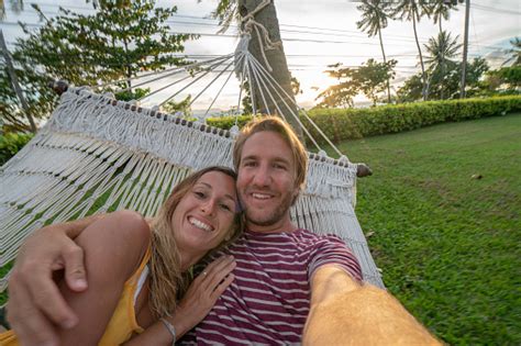 열 대 기후사람들이 여행 모바일 장치 기술에서 멋진 순간을 포착 하는 자연과 인생을 즐기는 휴가에 편안한 흰색 해먹에 젊은 부부 복용 Selfie 2명에 대한 스톡 사진 및