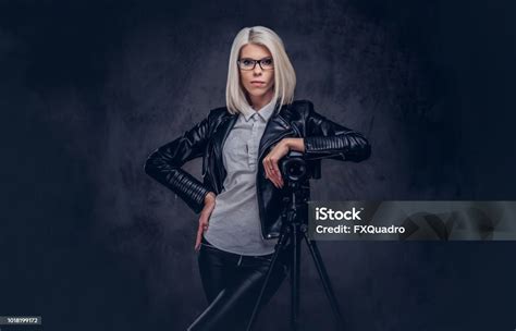 최신 유행 옷 기대는 스튜디오에서 삼각대와 함께 전문 카메라에는 카메라에 보이는 하는 동안 포즈에 스마트 금발 여성 사진 작가 가냘픈에 대한 스톡 사진 및 기타 이미지