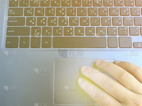 人的手触摸笔记本电脑的触控板，光标移动，柔和的光线聚焦在手指上。
