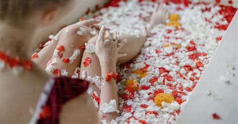 자연 피부 관리 개념입니다 열대 꽃이 있는 욕조에서 여성 다리에 선택적으로 초점을 맞춥니다 목욕에 누워 스파 절차를 즐기는