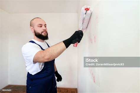 아파트에서 마무리 리노베이션을하고 건설 노동자 건설 현장에 콘크리트 벽실의 흰색 페인트 롤러 브러시 그림을 사용하여 전문 화가 계약자 홈 리노베이션 개념입니다 건설 산업에