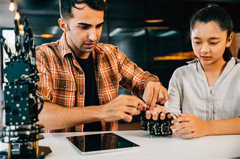 교사는 교실 디자인 및 기술 수업에서 로봇 팔을 사용하는 학생을 돕습니다 과학 교육에서 혁신 발견 및 코딩 기술을 육성합니다 로봇 손 기술 컨셉 10 11세에 대한 스톡