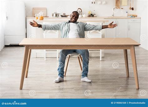 Happy African American Man Sitting On New Chair And Showing Wooden Table After Assembing