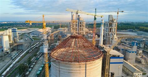 산업 생산 지역에서 높은 콘크리트 공장 구조와 타워 크레인으로 건설 중인 시멘트 공장의 조감도 제조 및 글로벌 산업 개념