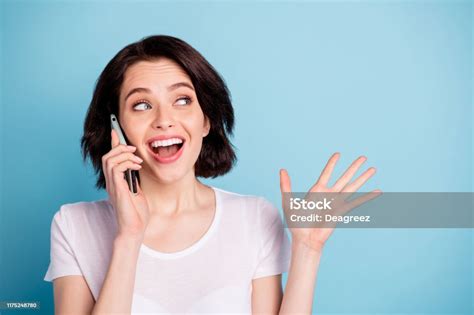 멋진 사랑스러운 깜짝 놀라게 한 멋진 쾌활한 쾌활한 꿈꾸는 소녀의 클로즈업 초상화는 밝은 생생한 빛에 고립 된 전화로 이야기하는 활기찬 파란색 청록색 색상 배경 갈색 머리에