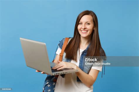 배낭 들고와 작업을 사용 하 여 노트북 Pc 컴퓨터 파란색 배경에 고립에 데님 옷에서 젊은 매력적인 행복 한 여자 학생 대학에서 교육입니다 광고에 대 한 공간을 복사 합니다