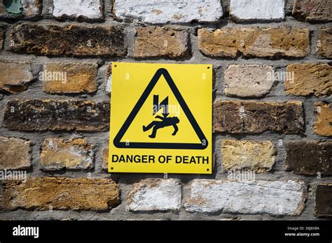 Yellow Danger Of Death Warning Sign Mounted On A Wall Featuring A