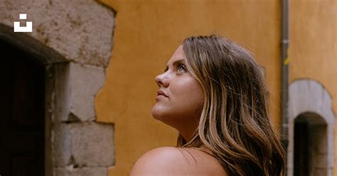 낮 동안 갈색 콘크리트 벽 근처에 서 있는 빨간색과 파란색 꽃무늬 오프 숄더 드레스를 입은 여자 사진 Unsplash의 무료 리스본 이미지