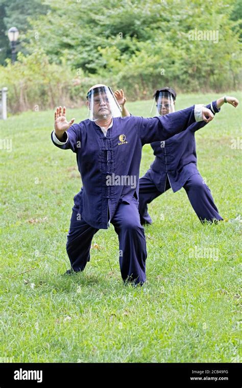 An Asian American Couple Wearing Face Shields Attend A Tai Chi Class