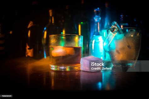 병 나무 막대 근접 촬영에 위스키의 유리 보기 빛과 연기와 어두운 배경에 흐리게 얼음 반사 나무 표면에 위스키의 단일 유리 0명에 대한 스톡 사진 및 기타 이미지 Istock