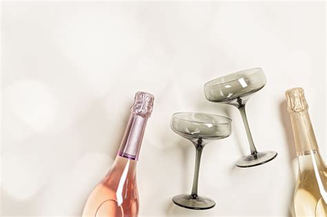 샴페인 병과 샴페인 잔은 베이지색 배경에 회색 유리로 되어 있고 공간을 복사한다 미니멀 스타일 여름 음료 아이디어 스파클링 화이트 와인과 로제 와인의 최고 전망 아름다운 빛