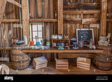 A Rustic Candy Bar Setup In A Wooden Barn With Various Sweets In Glass Jars And A Chalkboard