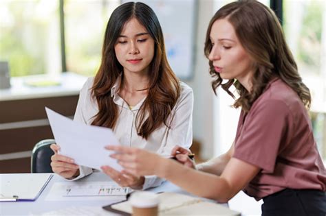 비즈니스 사무실 여성의 개념 비즈니스 여성은 워크스테이션의 책상에서 노트북을 사용하여 문서 및 비즈니스 투자 그래프 데이터를 분석하는 투자 계획에 대해 작업하는 동안 미소를