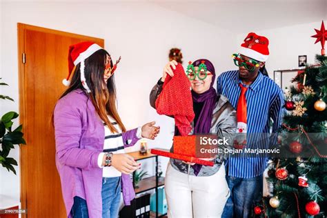 사무실에서 함께 새해를 축하하는 동료들 크리스마스 트리 앞에 서서 선물을 나누는 모습 12월 31일에 대한 스톡 사진 및 기타