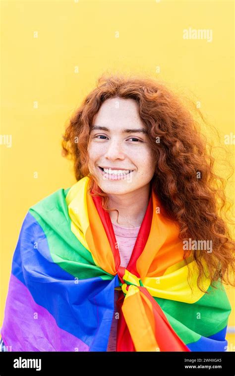 Red Haired Non Binary Gay Man With Rainbow Flag Over Yellow Background